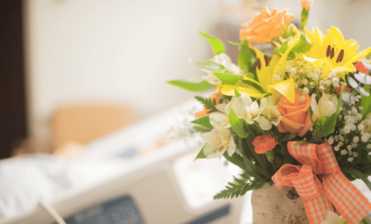 A bouquet of Get Well Soon flowers at a hospital bedside.